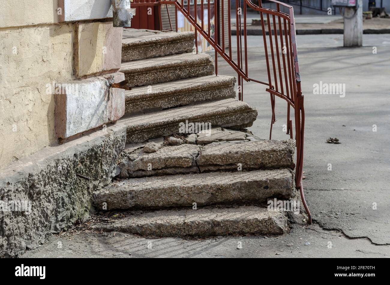 Old crumbling stone staircase with metal railings. Rusty railings line ...
