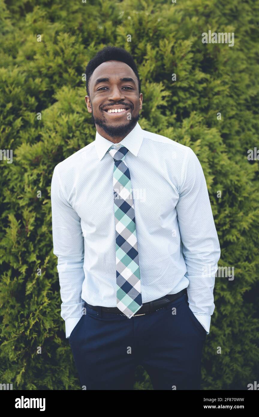Vertical shot of a handsome African-American male posing on a green ...