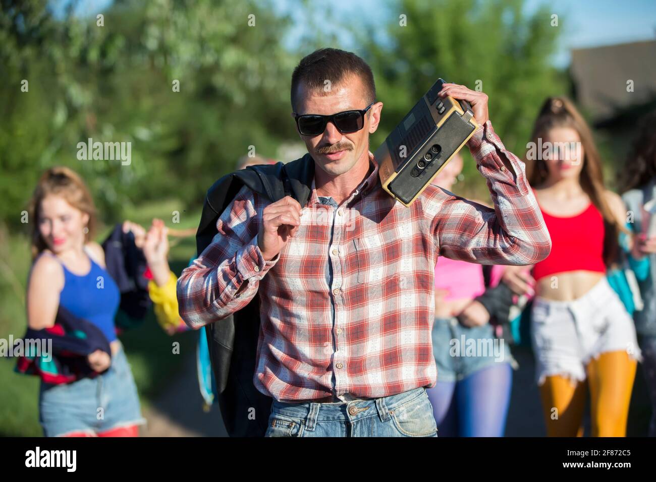 Funny man with a cassette recorder in front of a group of girls. People ...