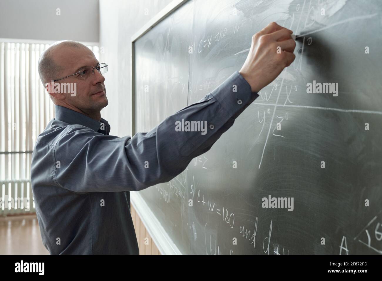 Mature professor of university in smart casualwear standing in front of ...