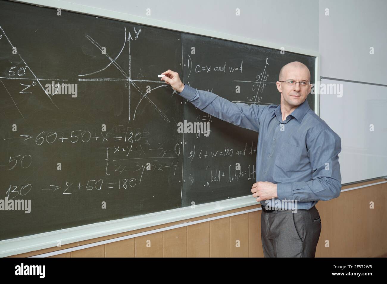 Confident mature professor standing in front of blackboard in lecture ...
