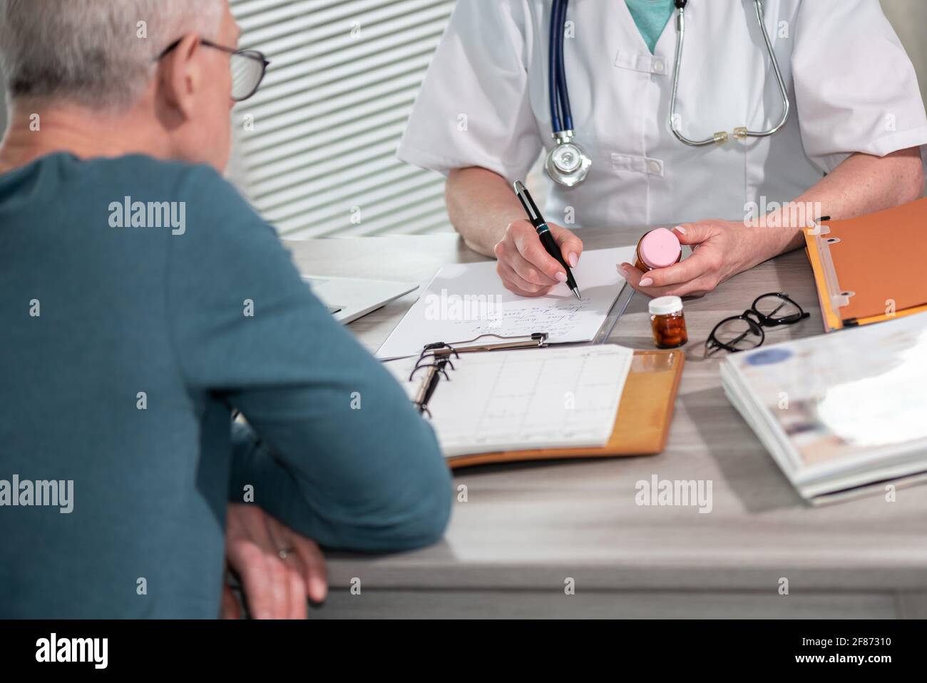 Female doctor writing prescription to her patient in medical office ...