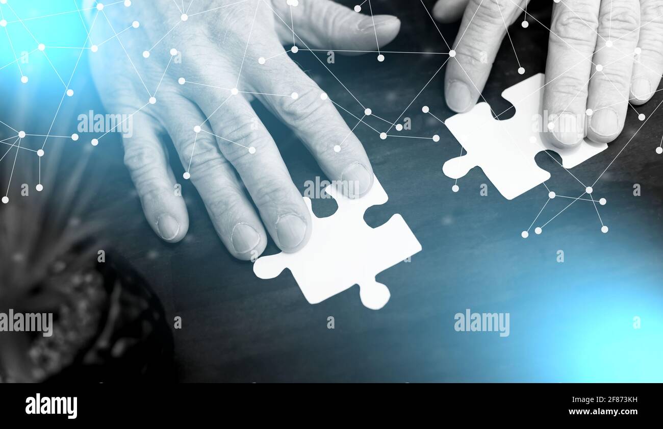 Hands joining two puzzle pieces, teamwork concept; multiple exposure ...