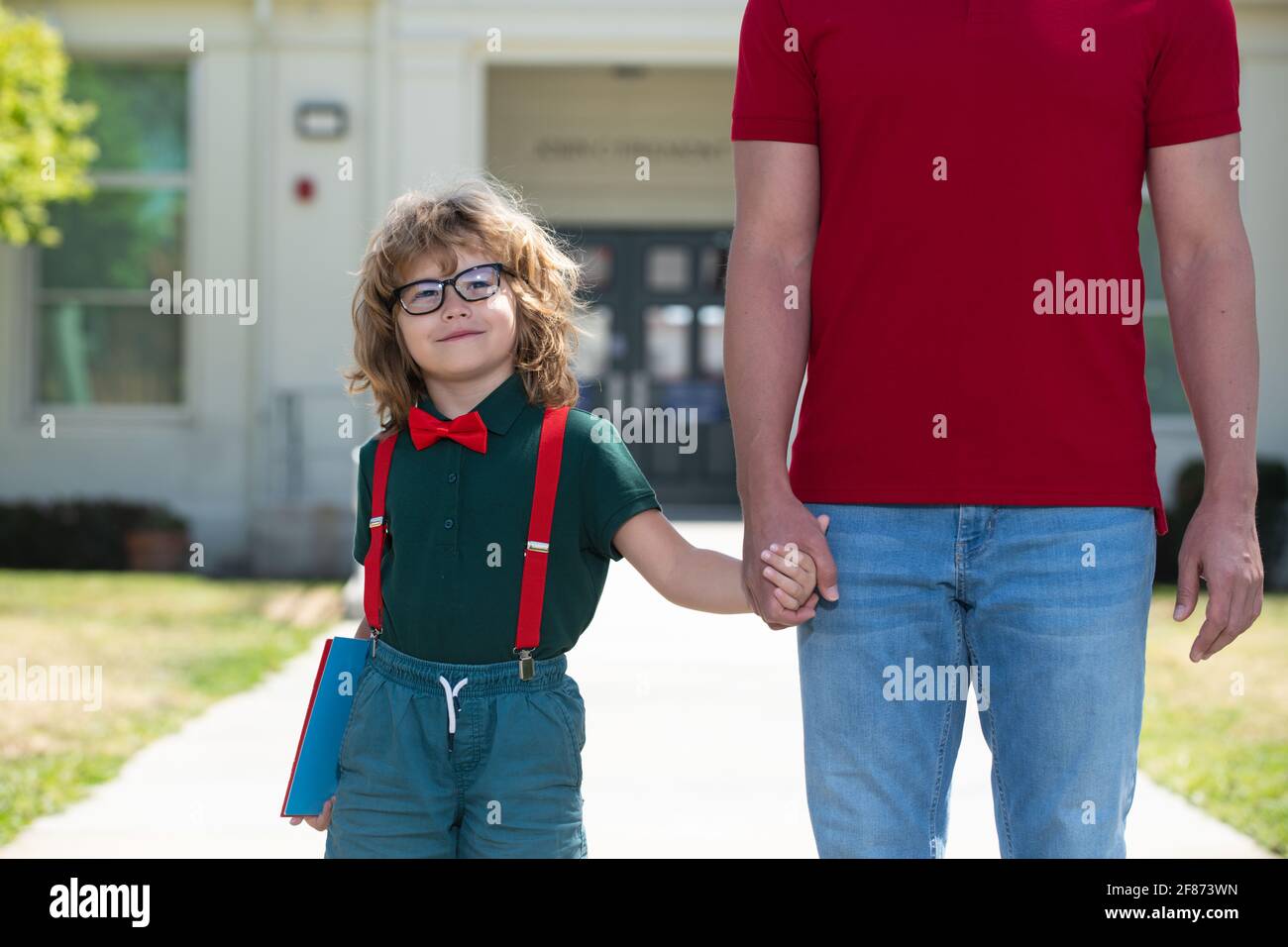 Portrait of happy nerd pupil holding teachers hand. School, family ...