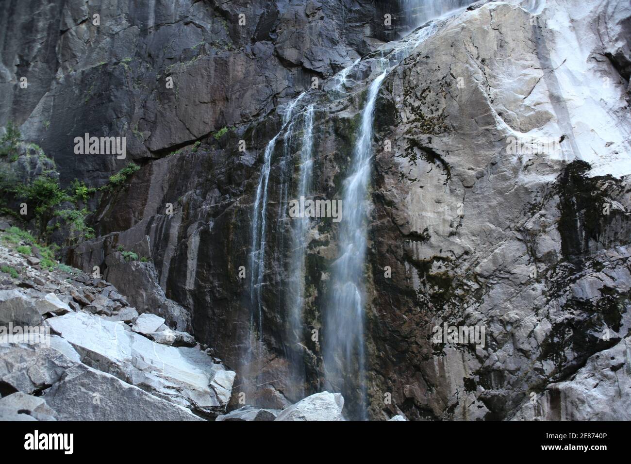 Narrow waterfall falling between rocky rough cliff stone walls in the ...