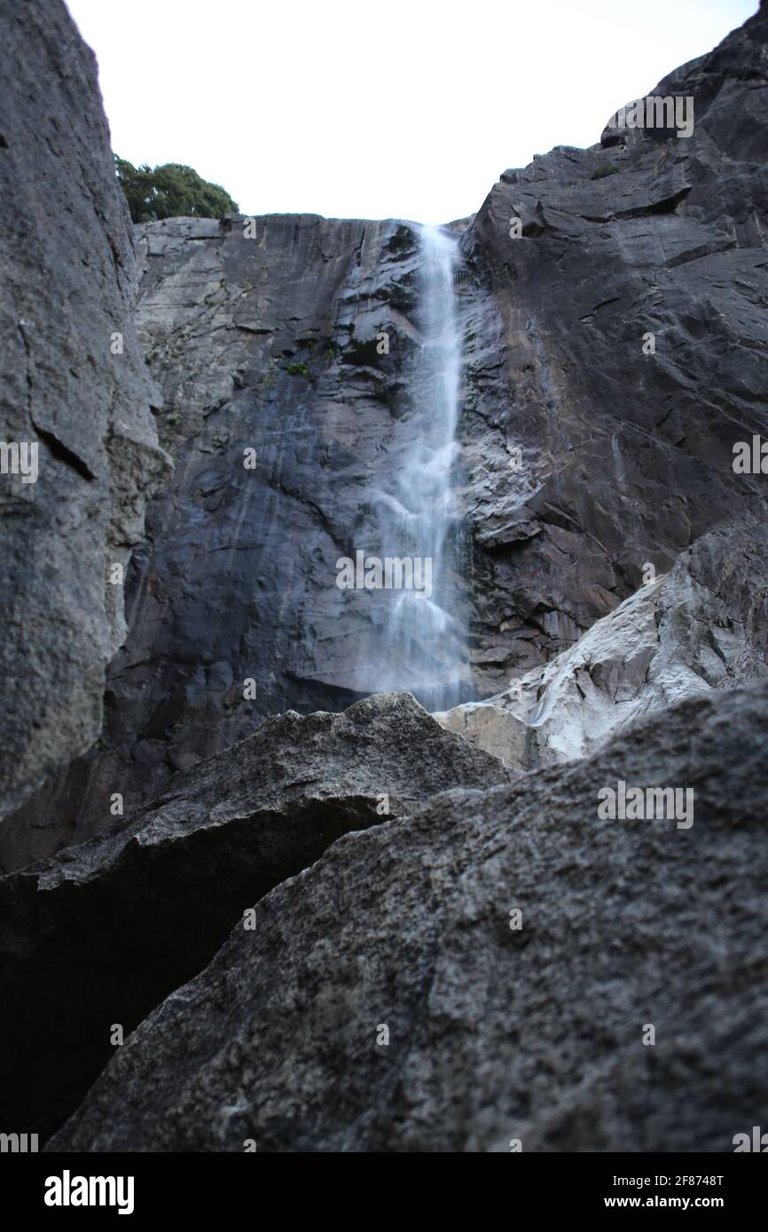 Narrow waterfall falling between rocky rough cliff stone walls in the ...
