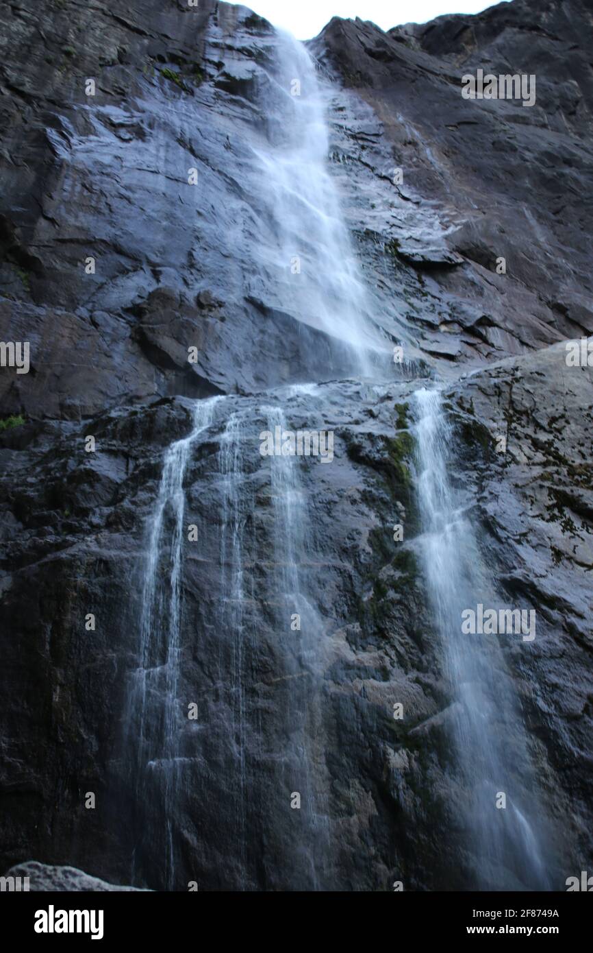 Narrow waterfall falling between rocky rough cliff stone walls in the ...
