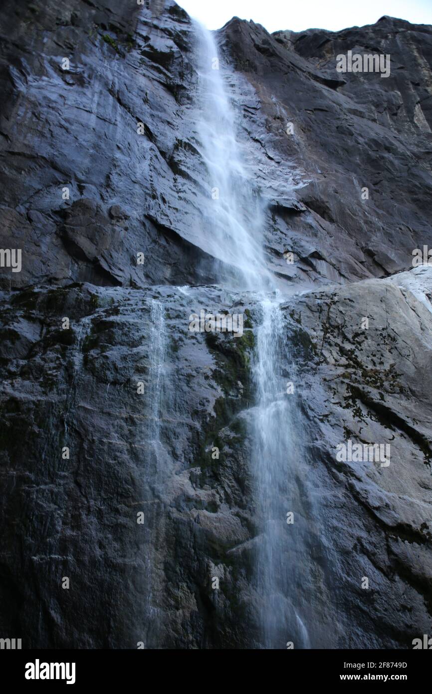 Narrow waterfall falling between rocky rough cliff stone walls in the ...