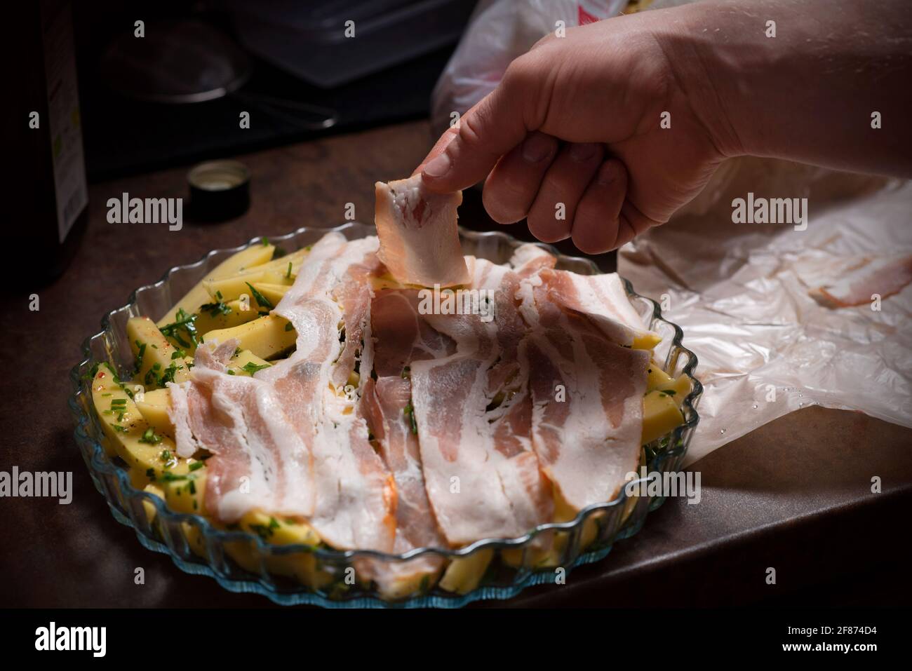 A chef shows the preparation process of bacon with potatoes and parsley ...