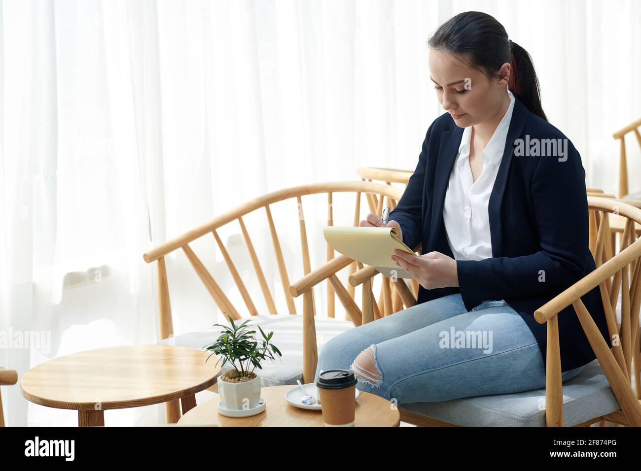 Young woman spending morning in coffeeshop, drinking coffee and writing ...