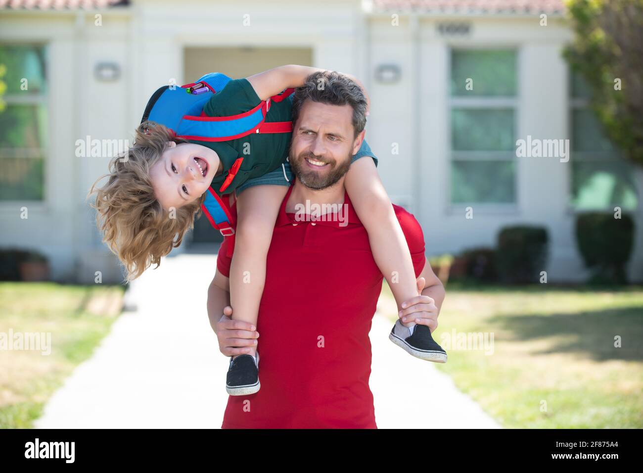 School boy going to school with father. Man giving son piggyback ride ...