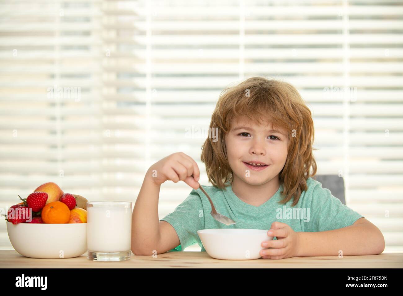 Portrait of cute child eating soup meal or breakfast having lunch by ...