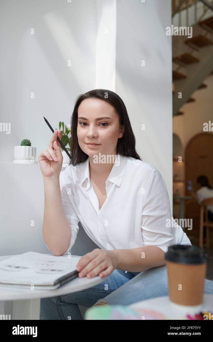 Portrait of talented creative young woman drawing sketches in ...