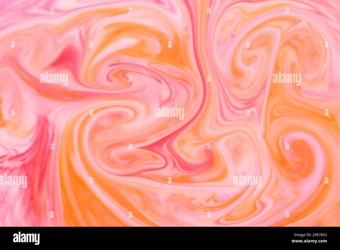 Abstract background texture of swirling or flowing orange and pink ink ...