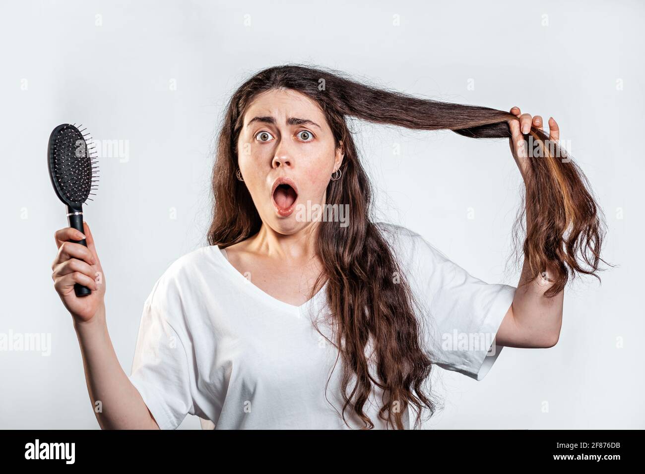 A frightened woman with long dark hair, screaming, holding a comb and a ...