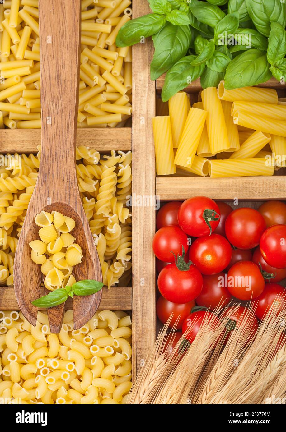 Wooden box with various classic italian pasta and basil with cherry ...