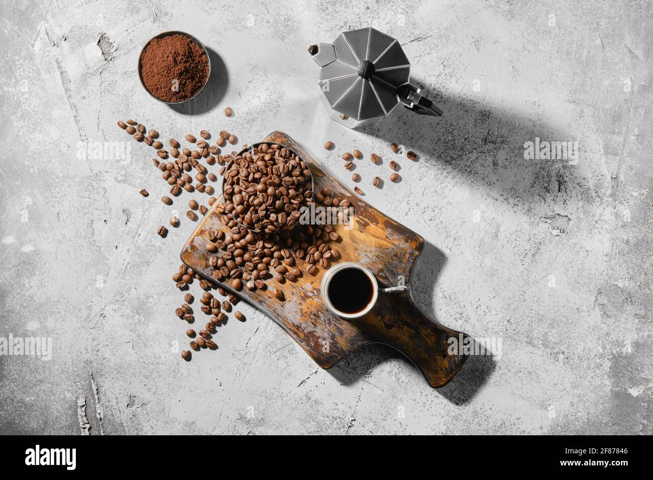 Overhead view of cup of espresso with coffee beans scattered on wooden ...