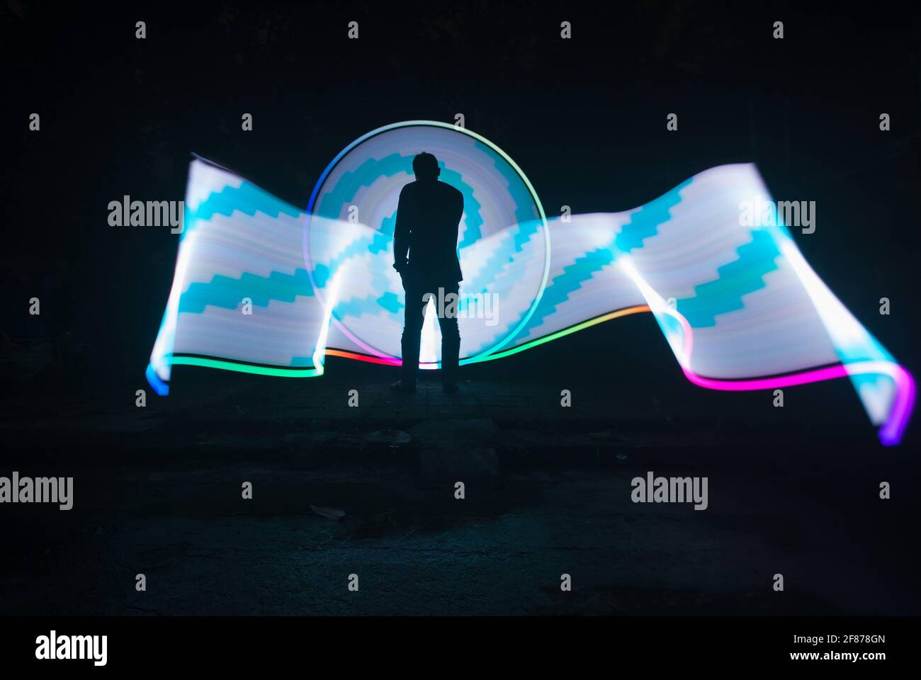 One person standing alone against beautiful color circle LED light ...