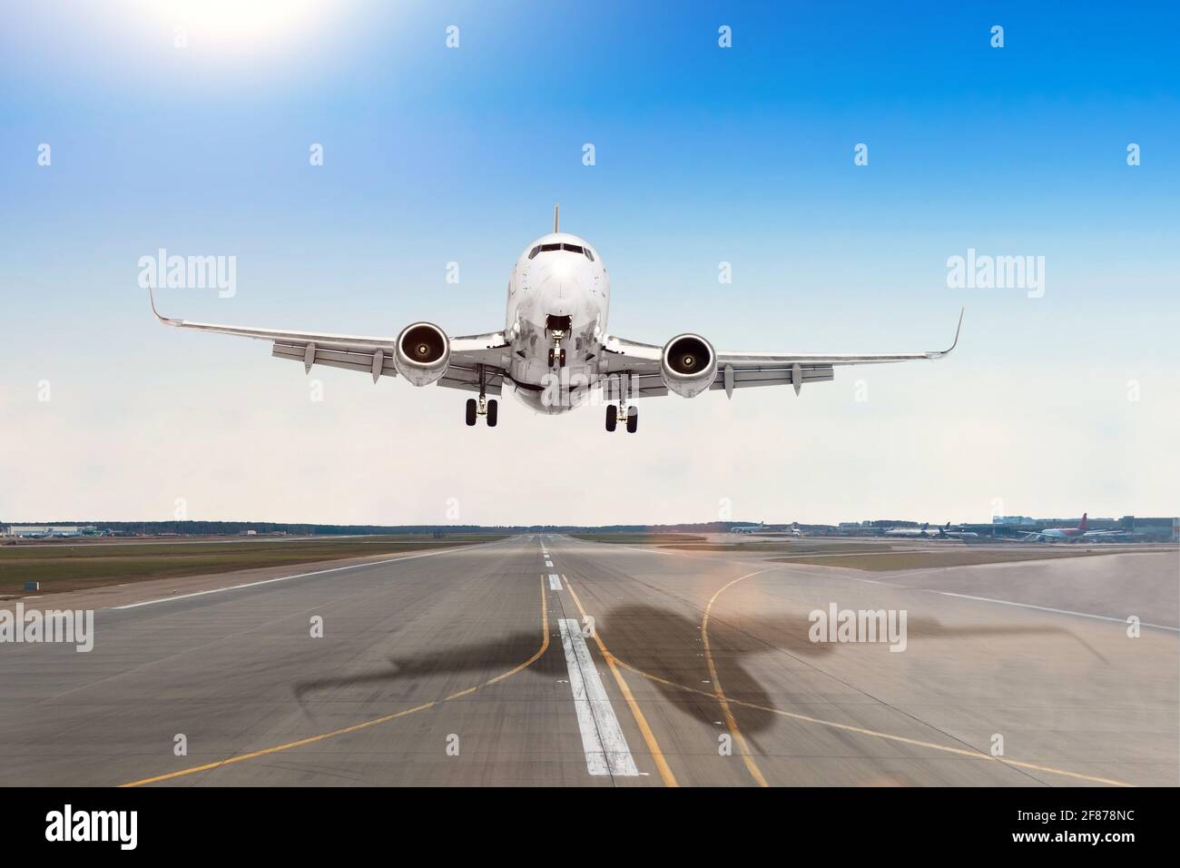 Passenger aircraft with a cast shadow on the asphalt landing on a ...