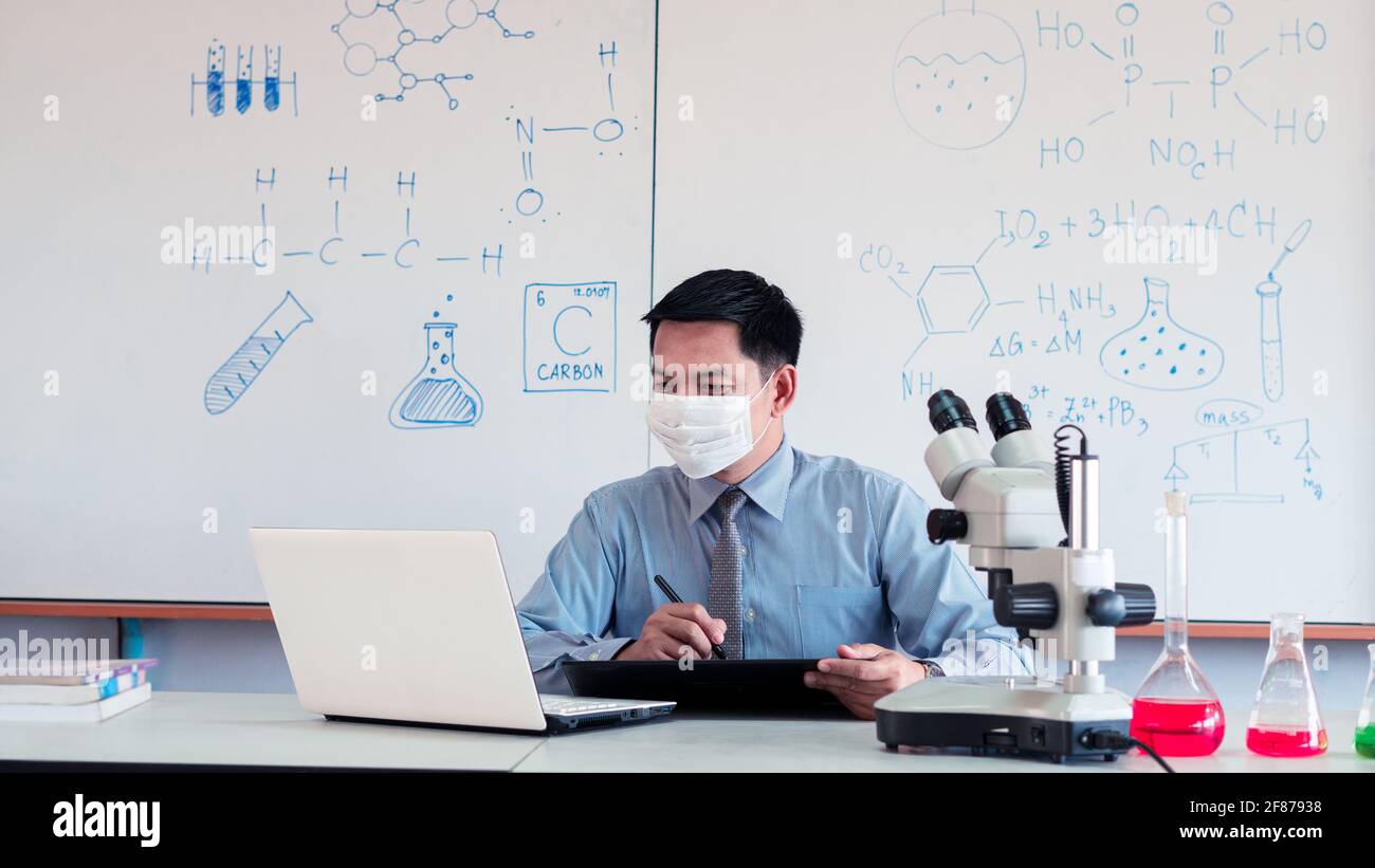 Science chemistry teacher teaching with microscope and laptop in the ...