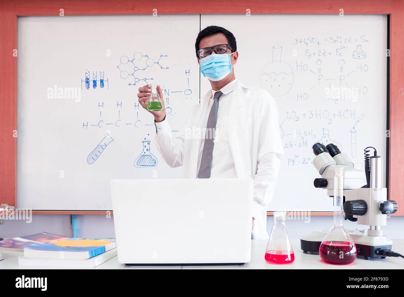 Science chemistry teacher teaching with microscope and laptop in the ...