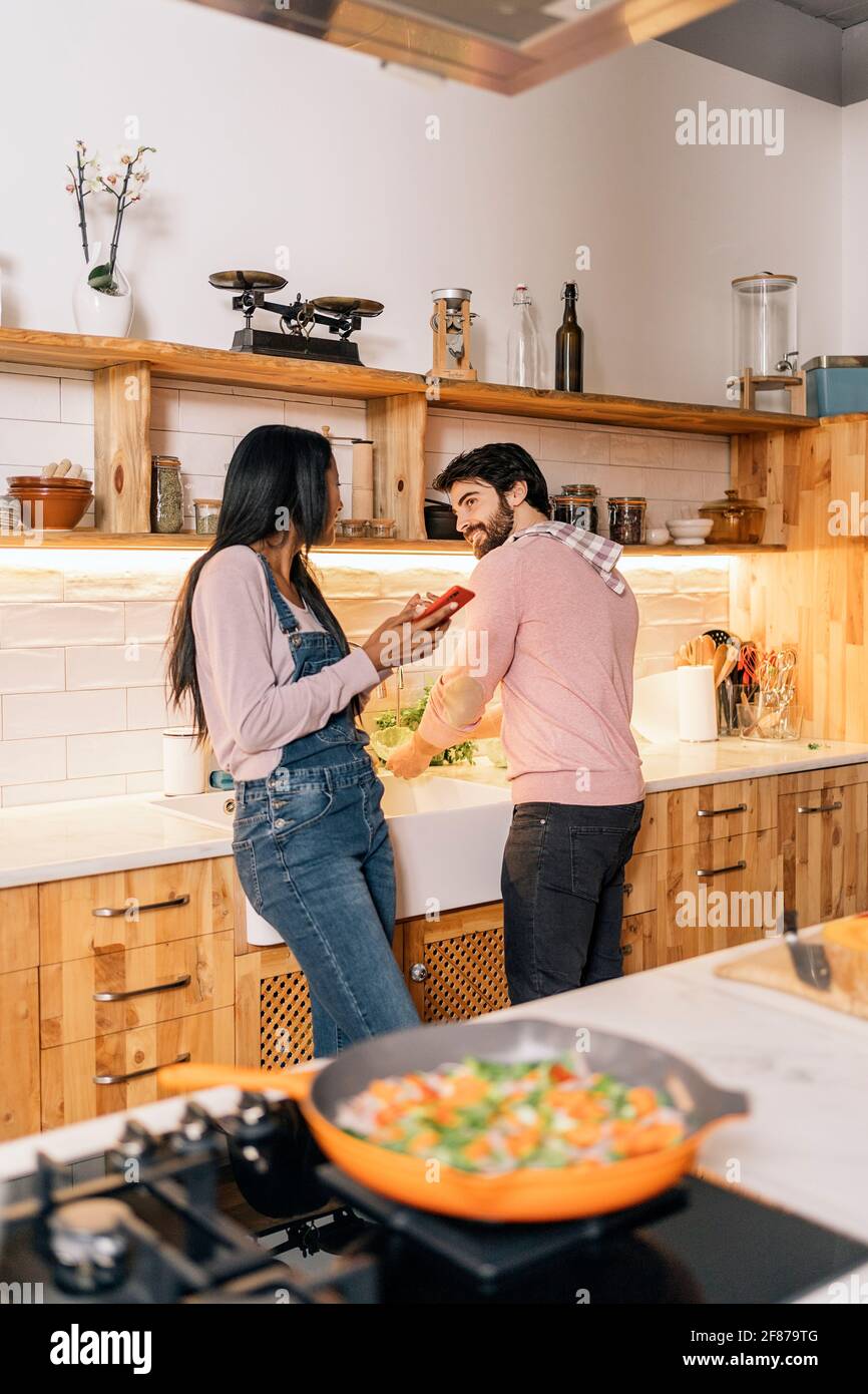 Beautiful black woman using her phone in the kitchen while her ...