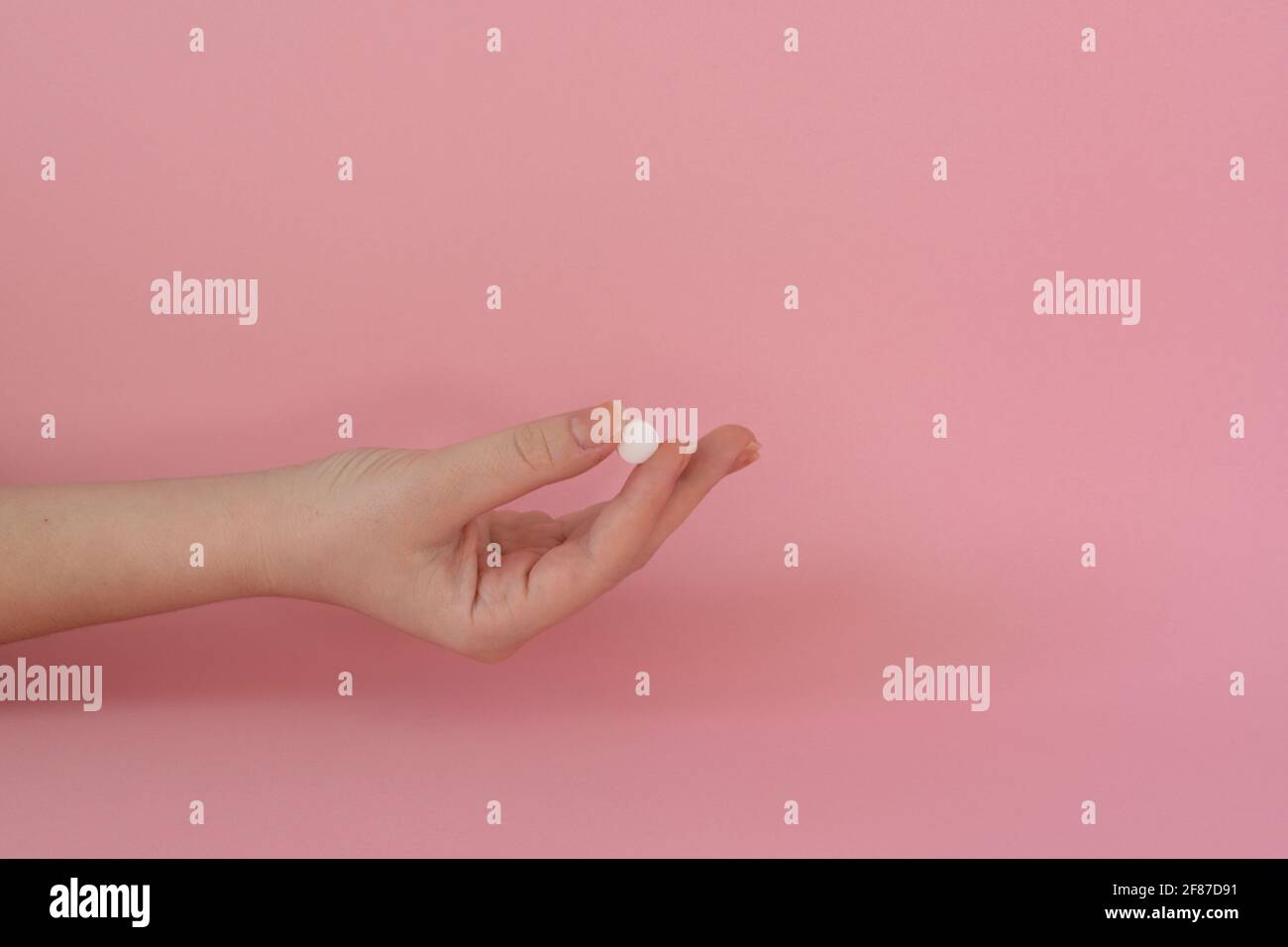 Vitamin tablet in a woman's hand, pink background Stock Photo - Alamy