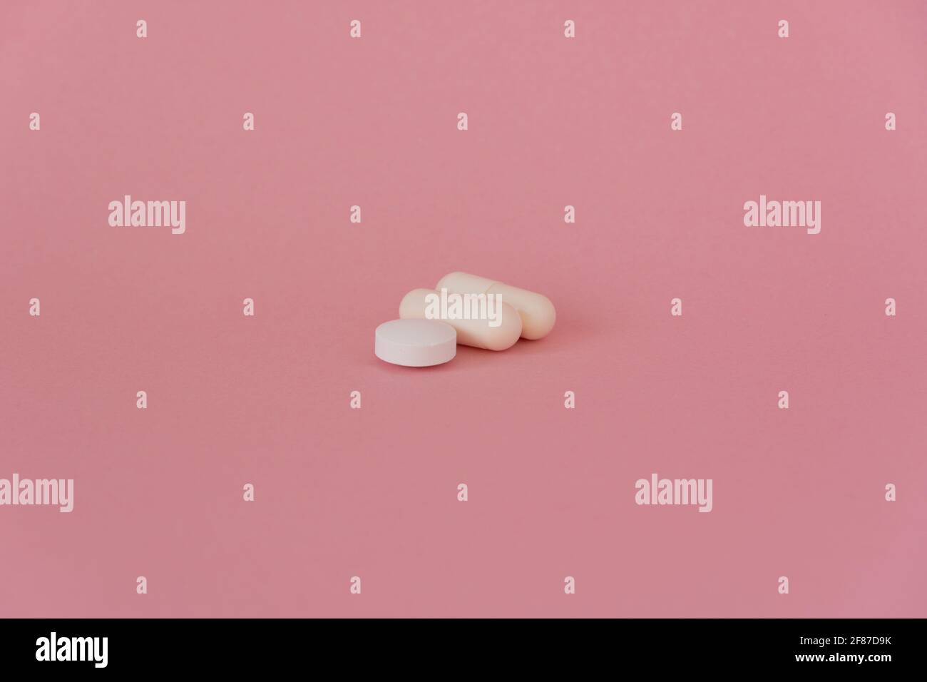 Three white tablets, vitamin tablets, on a pink background Stock Photo ...