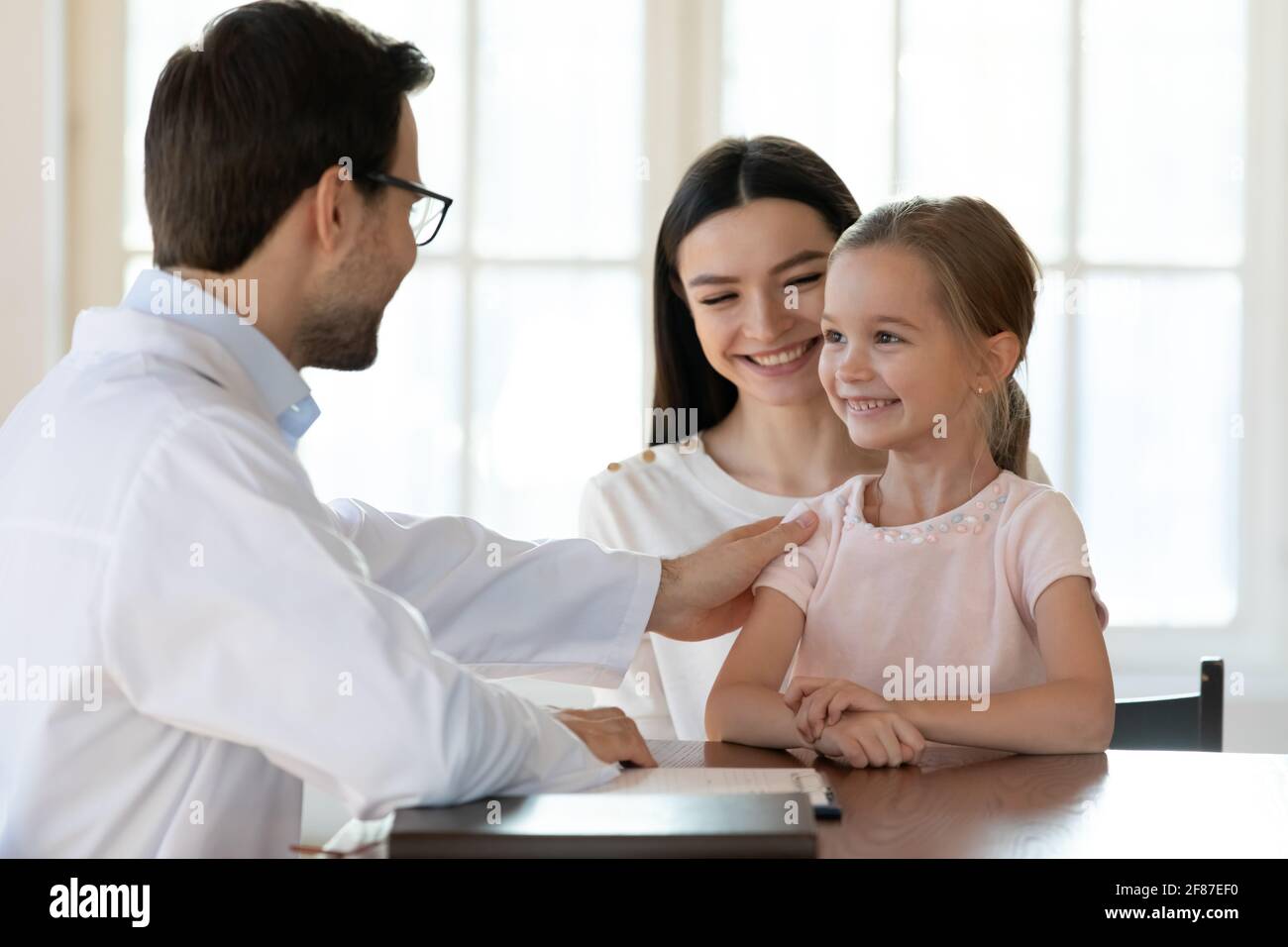 Caring male doctor comfort little girl patient in clinic Stock Photo ...
