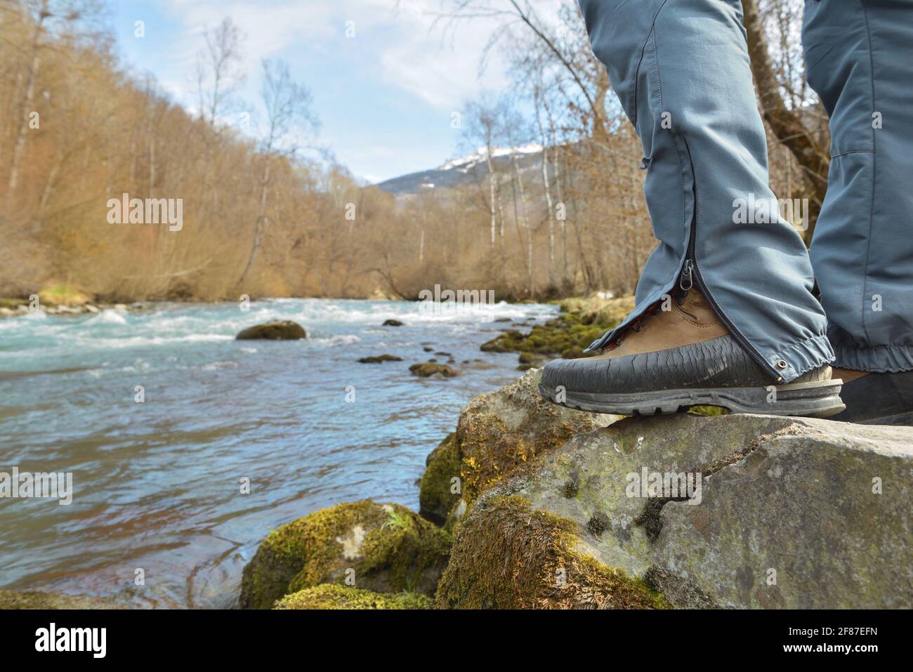 feet of a hiker wearing hiking shoes standing on a rock above an alpine ...