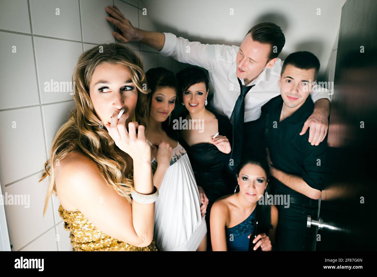 People in club and smoking a cigarette in the toilet and have lots of ...