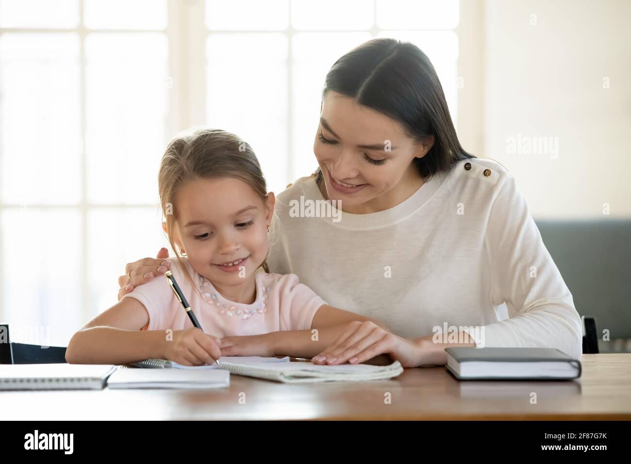 Happy young mom and little daughter do homework Stock Photo - Alamy