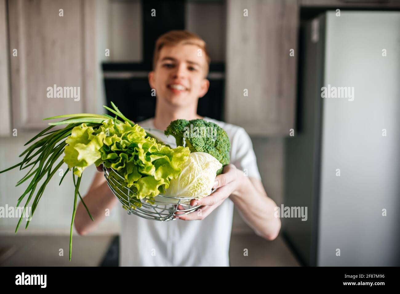 healthy and fresh food. Young vegetarian man is cooking salad in ...
