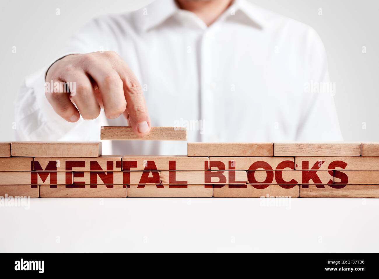 Businessman builds a structure of wooden blocks with the word mental ...