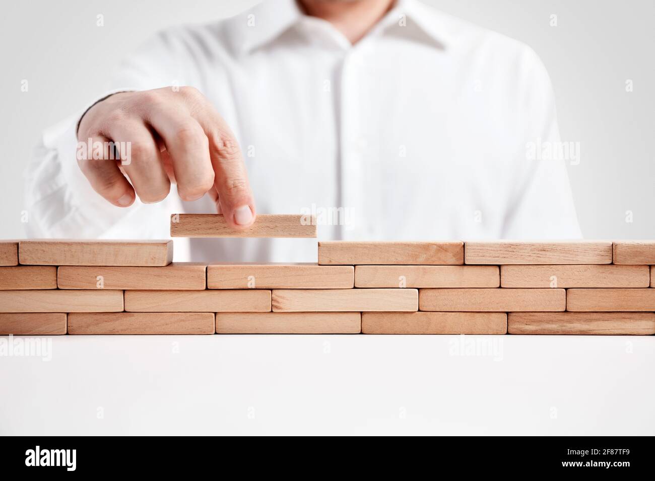 Businessman builds a barrier of wooden blocks. Security, safety ...