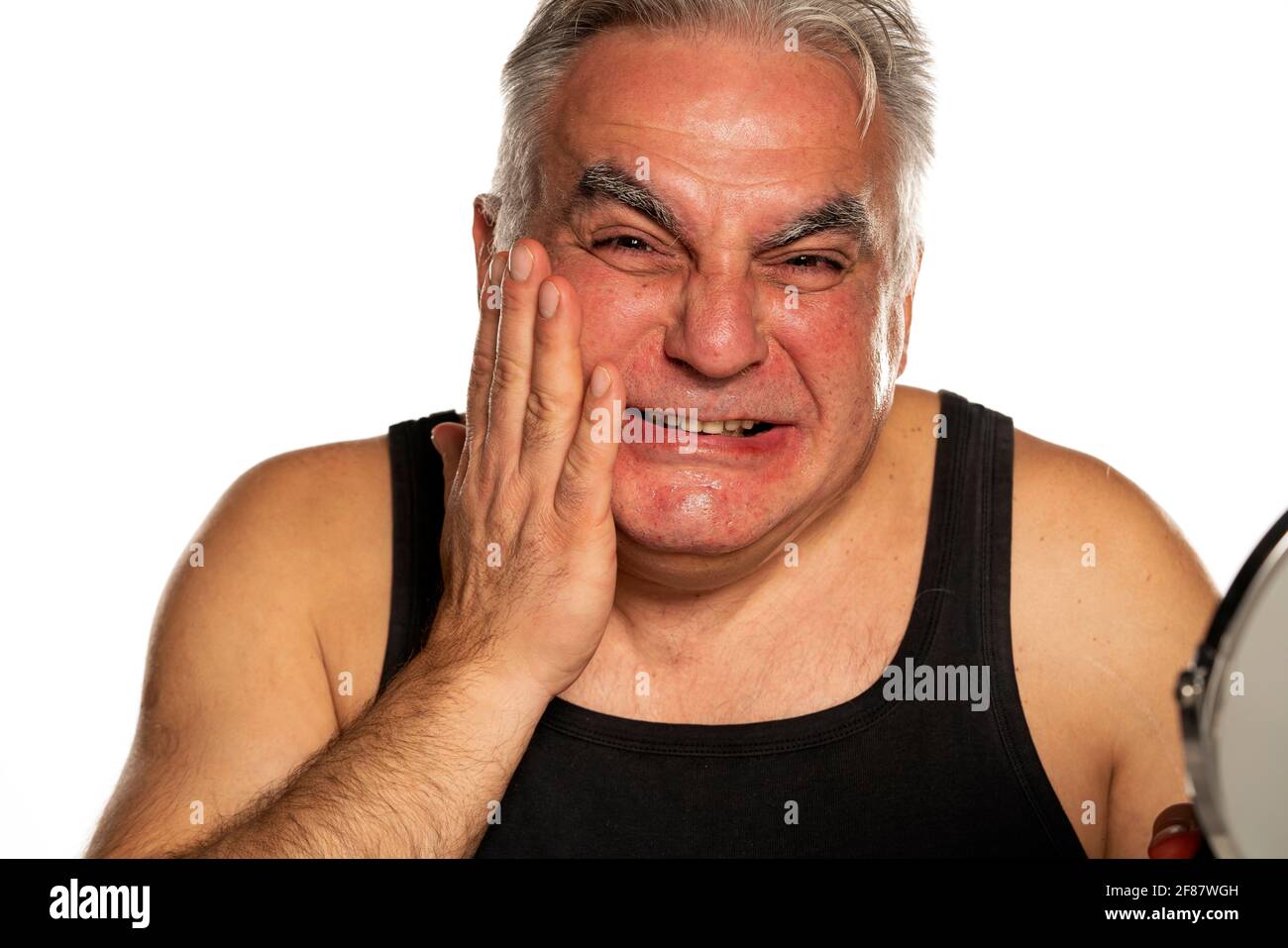 a middle-aged man feels pain on his face after shaving lotion on a ...