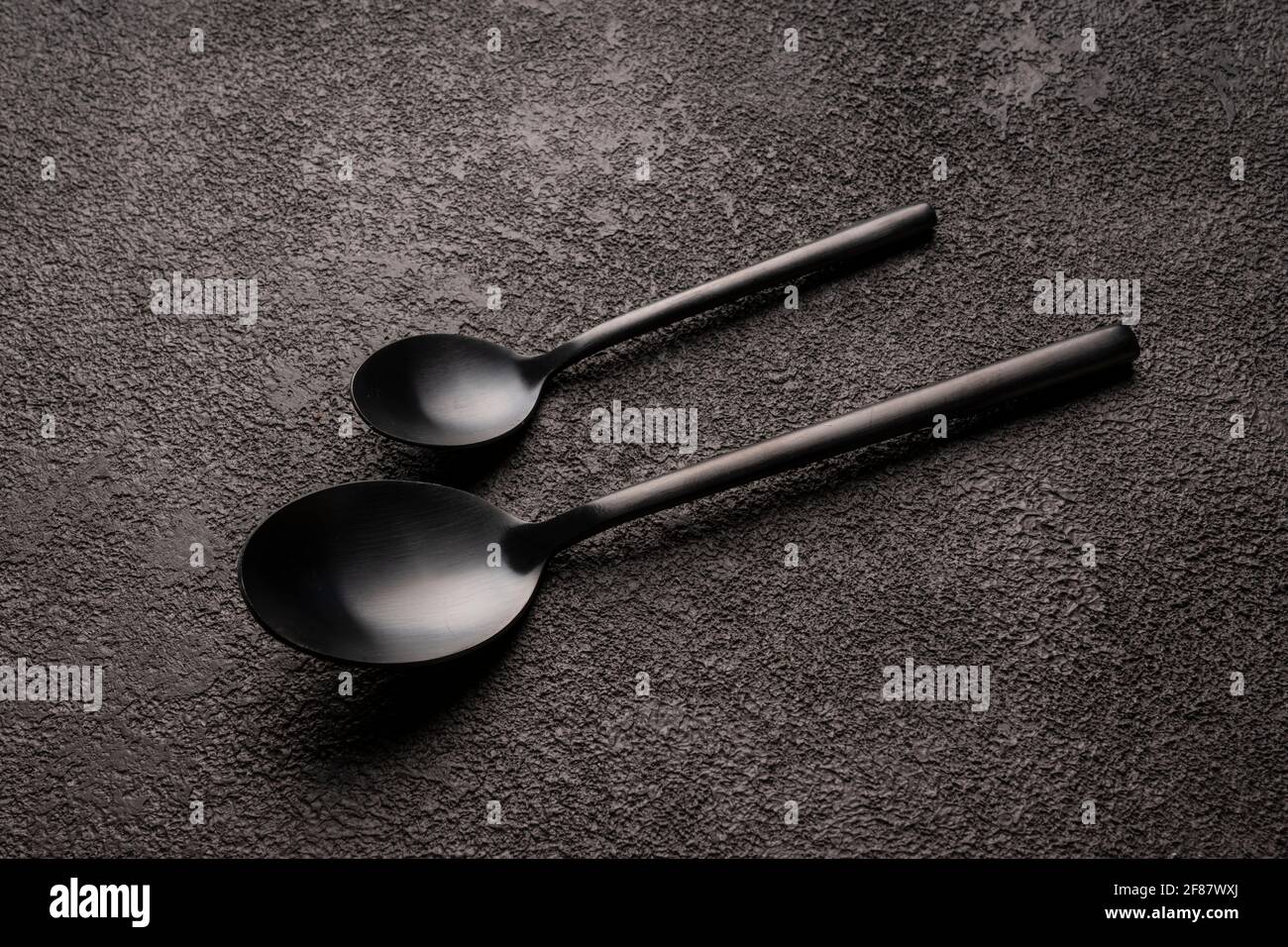 Spoons, teaspoons and regular ones, a couple. They're lying on a dark ...