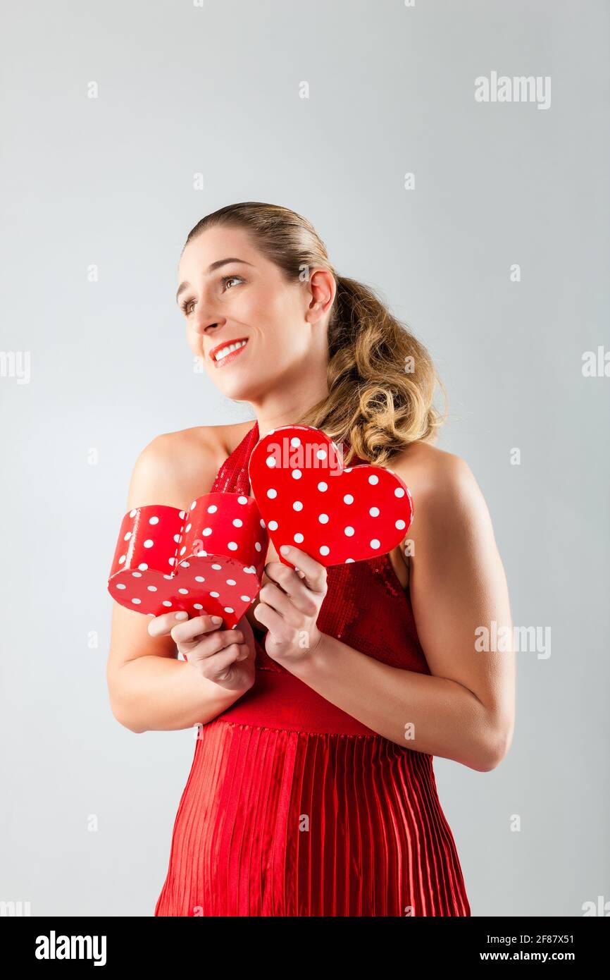 Woman opening heart shaped gift box with present for birthday or ...