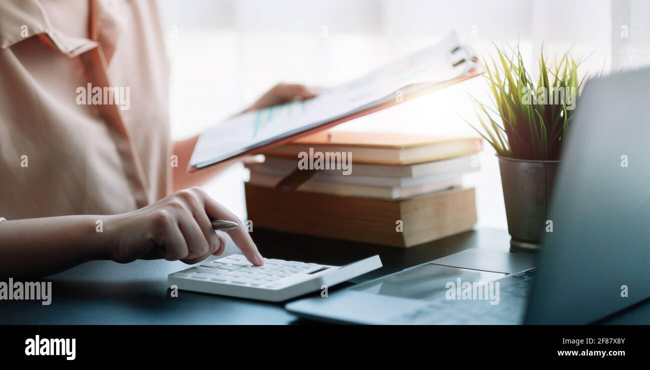 Business woman using calculator for do math finance on wooden desk in ...