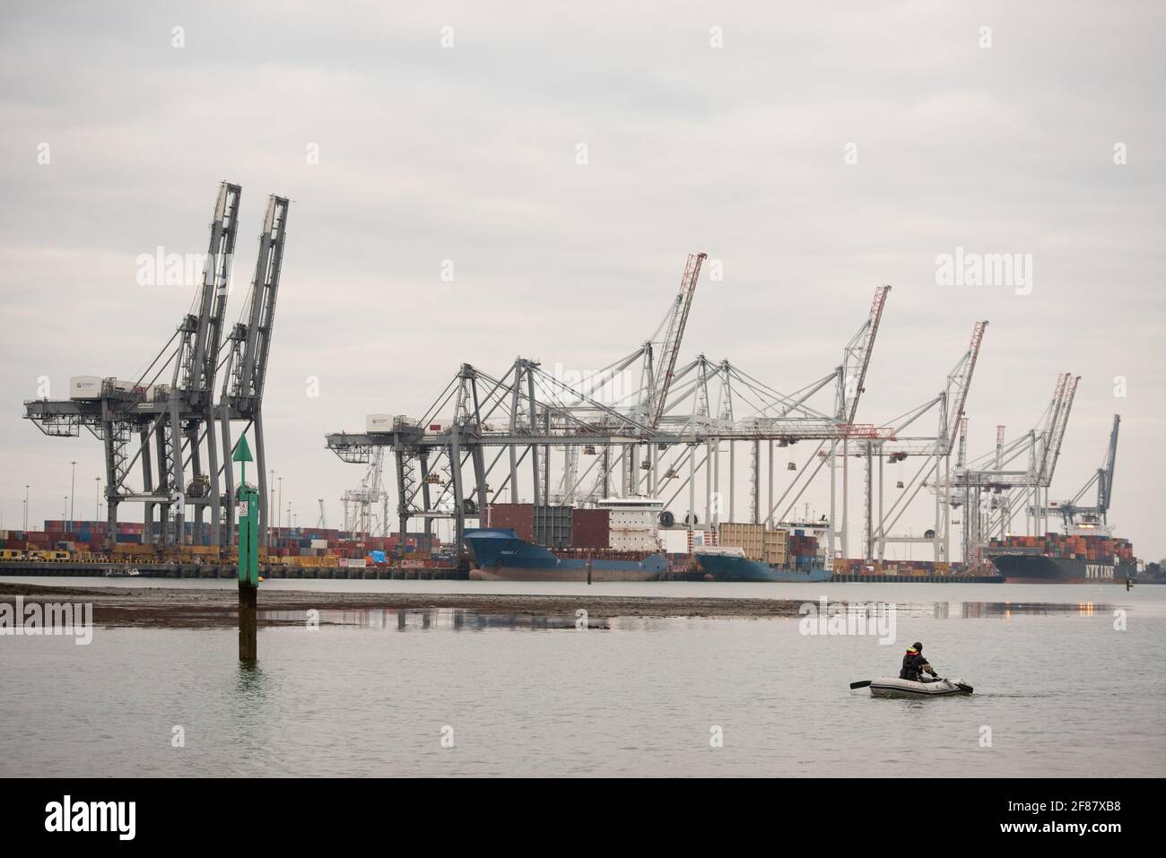 Southampton docks with man in dingy paddling along in foreground water ...