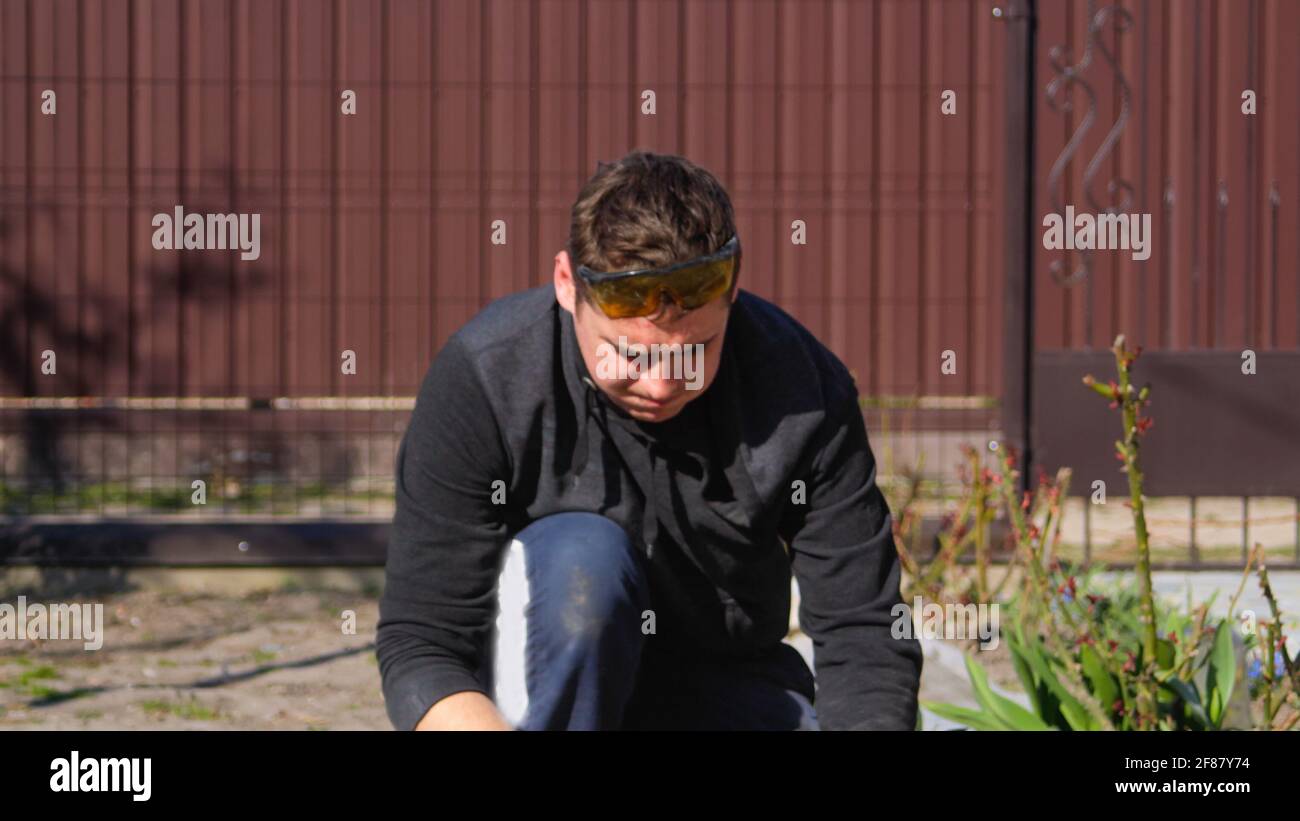 Defocus young construction worker in yellow glasses with puffy cheeks ...