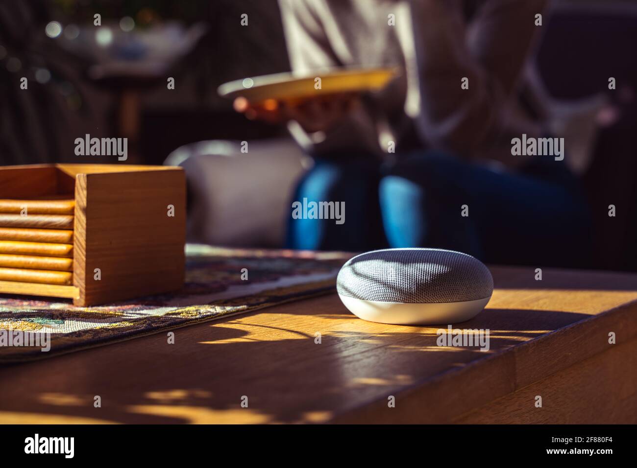 voice controlled smart speaker with a woman woman in the background in ...