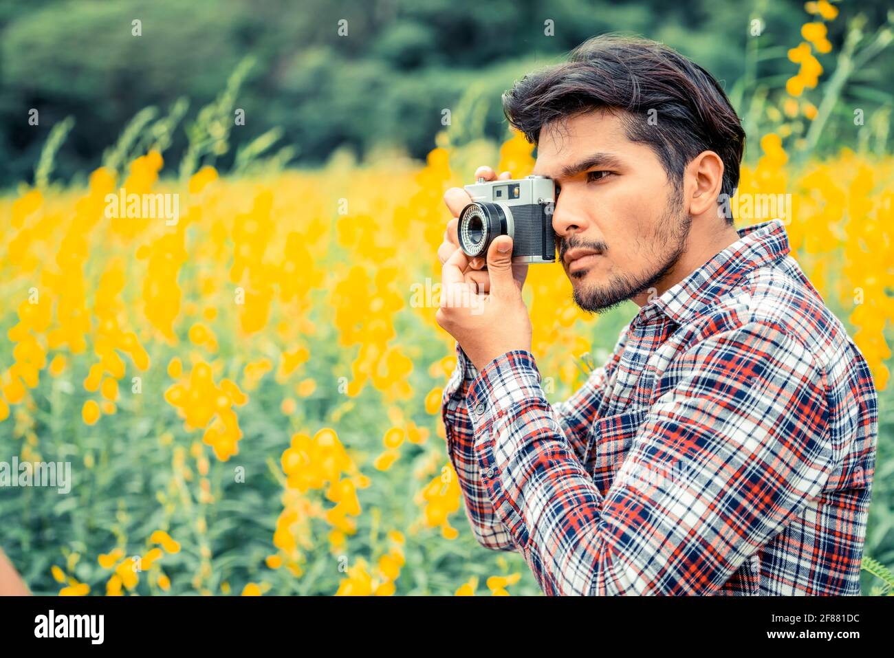 Young hipster man taking photo with old style camera with nature ...