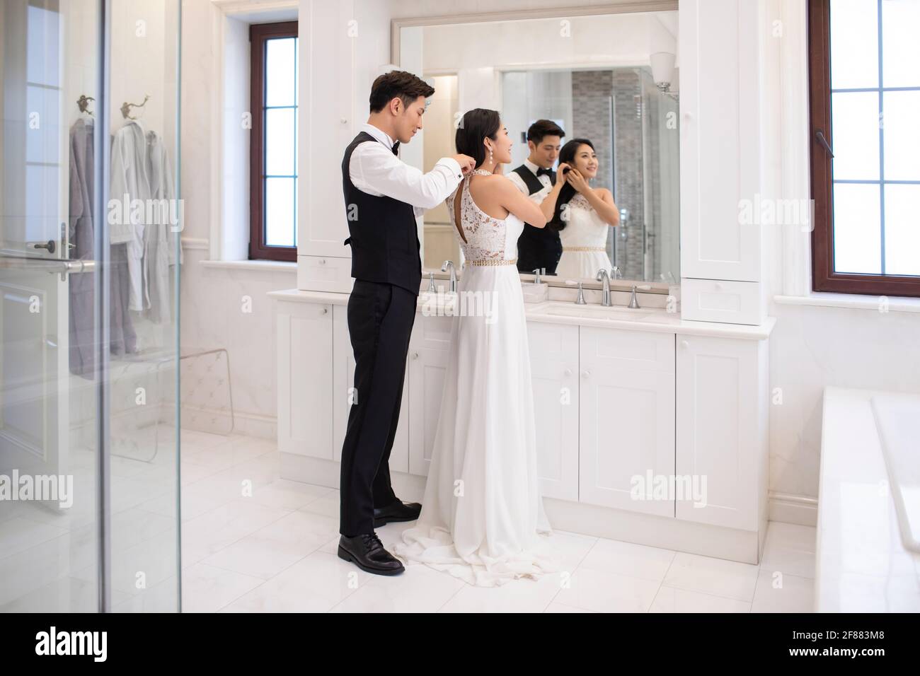 Happy young couple getting dressed in bathroom Stock Photo - Alamy