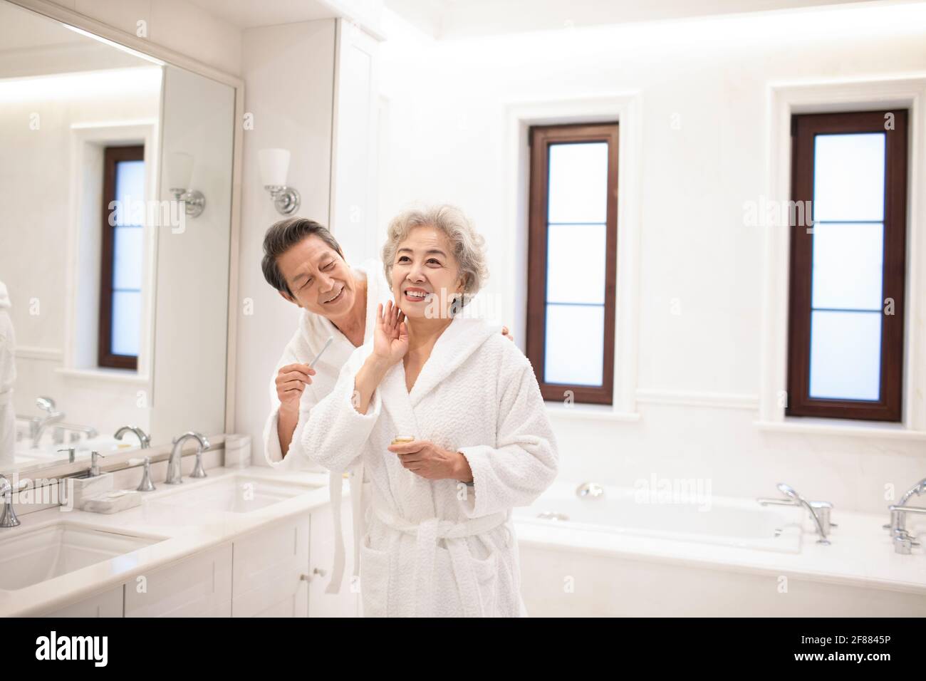 Happy senior couple going through their morning routine in bathroom ...