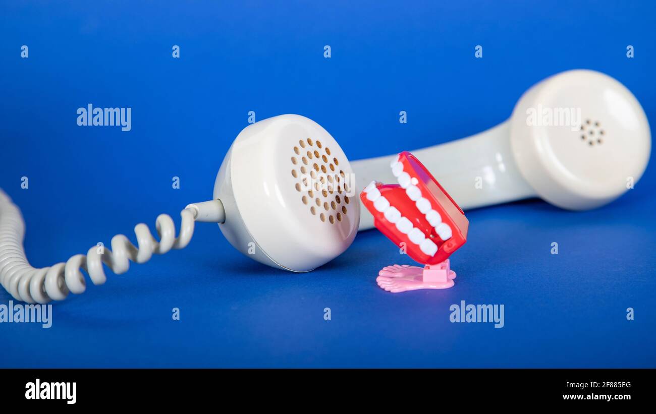 old telephone receiver and a toy mouth with teeth as symbol for ...