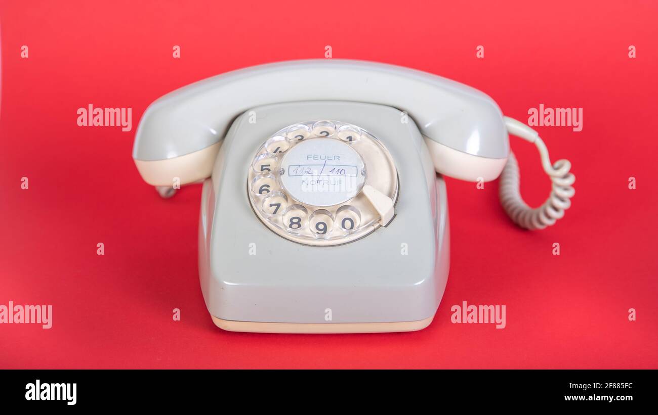 old grey telephone with dial plate, red background Stock Photo - Alamy