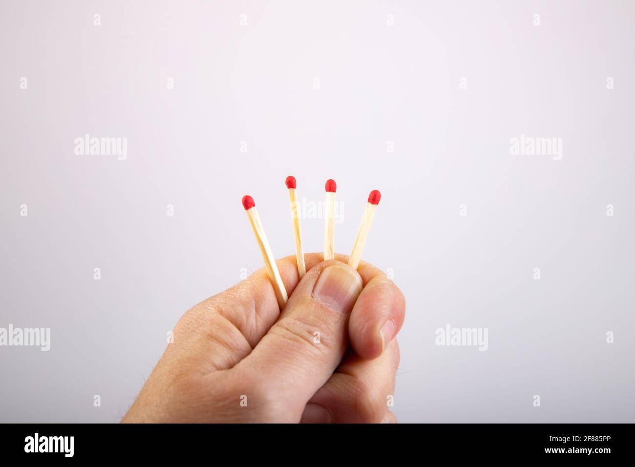 four match sticks in a hand, one is shorter, as symbol for to lose out ...