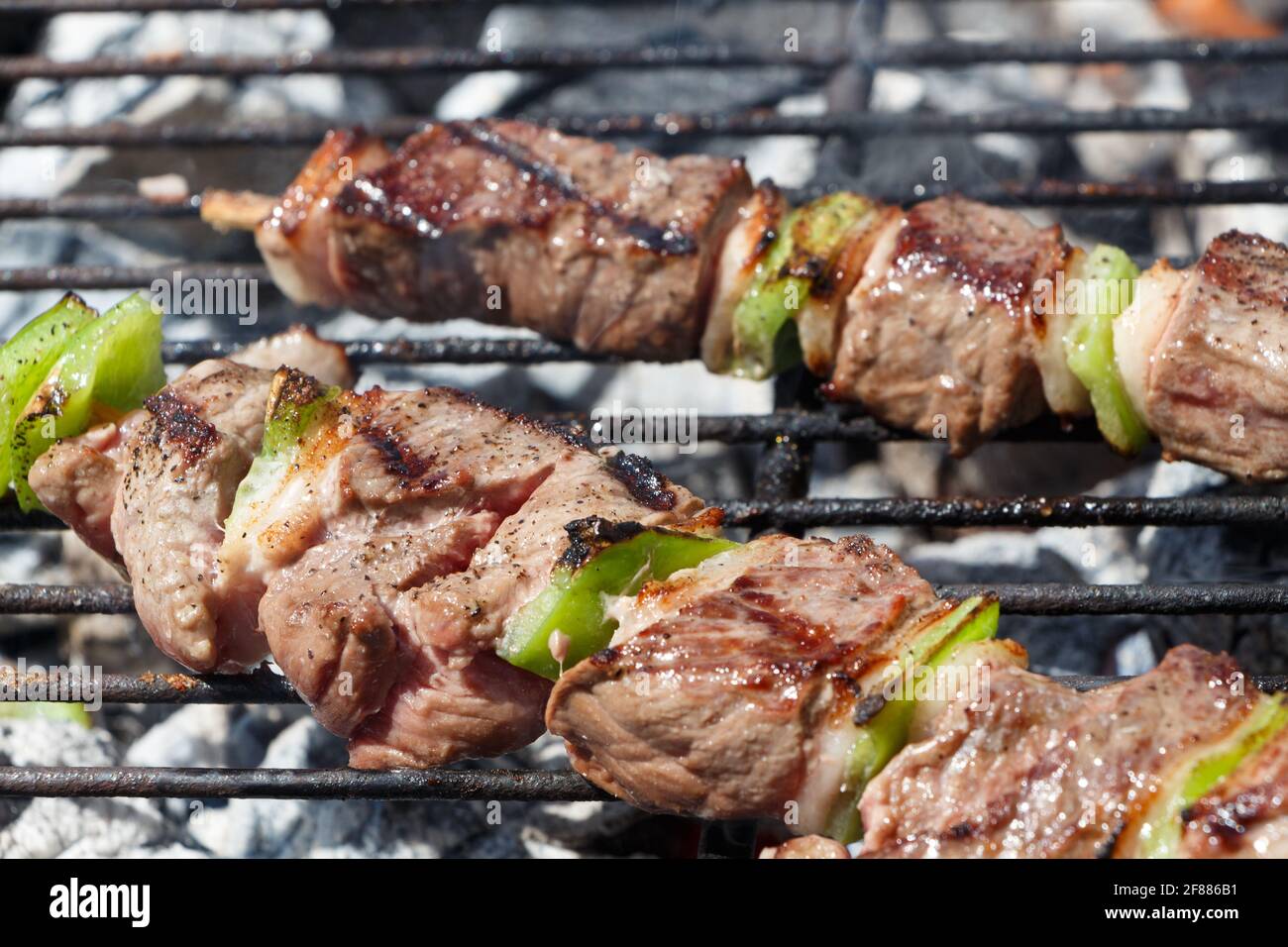 Beef brochettes grilling on the grid of a barbecue Stock Photo - Alamy