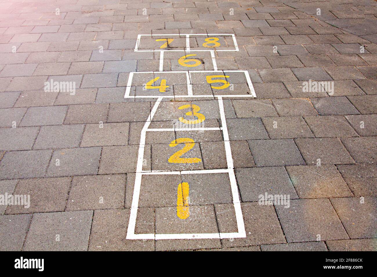 a hopscotch game painted white and yellow on a sidewalk block Stock ...